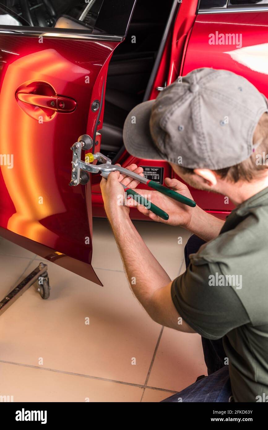 The technician removes dents on the car using the method without ...