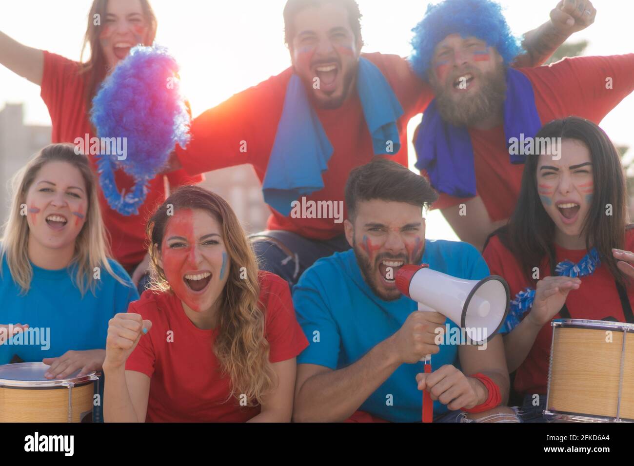 Football fans screaming, with red and blue shirts in the stadium. Group ...