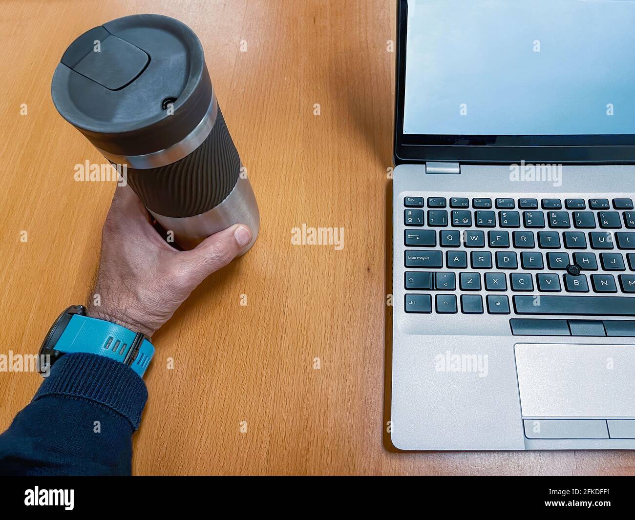 top view of a light wood work desktop with a laptop computer and a hand ...