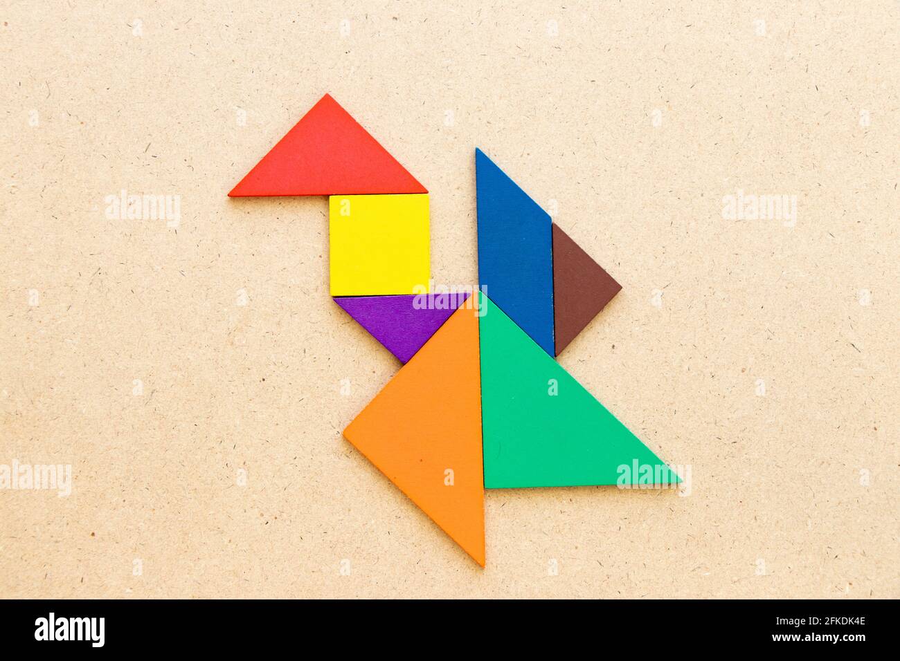 Color tangram puzzle in flying bird or dragon shape on wood background ...
