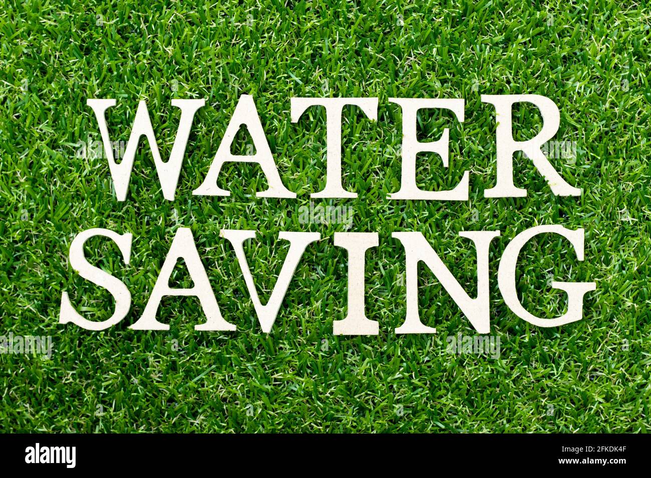 Wood alphabet letter in word water saving on green grass background ...