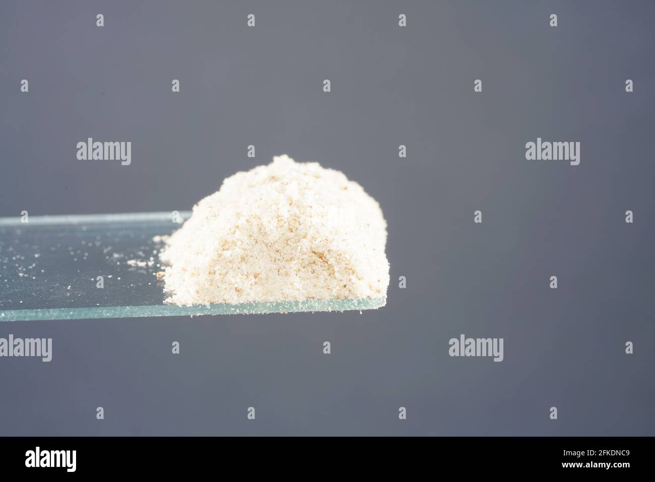 Closeup of white powder looking like drugs in front of a gray ...