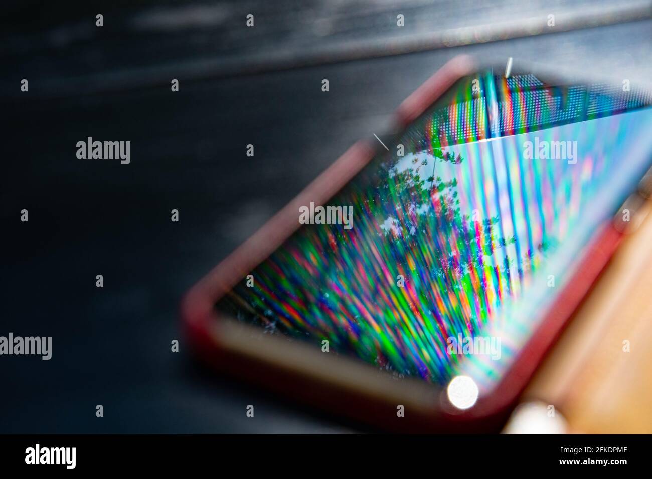 Vibrant rainbow rays reflect in mobile phone screen surface with dark ...