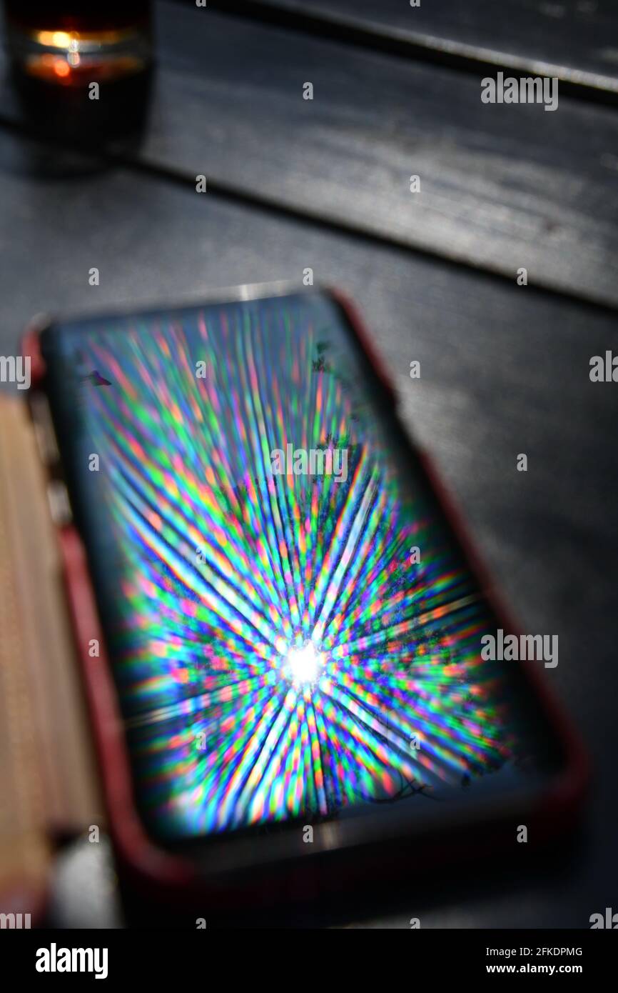 Bright rainbow rays reflect in mobile phone screen surface with blurred ...