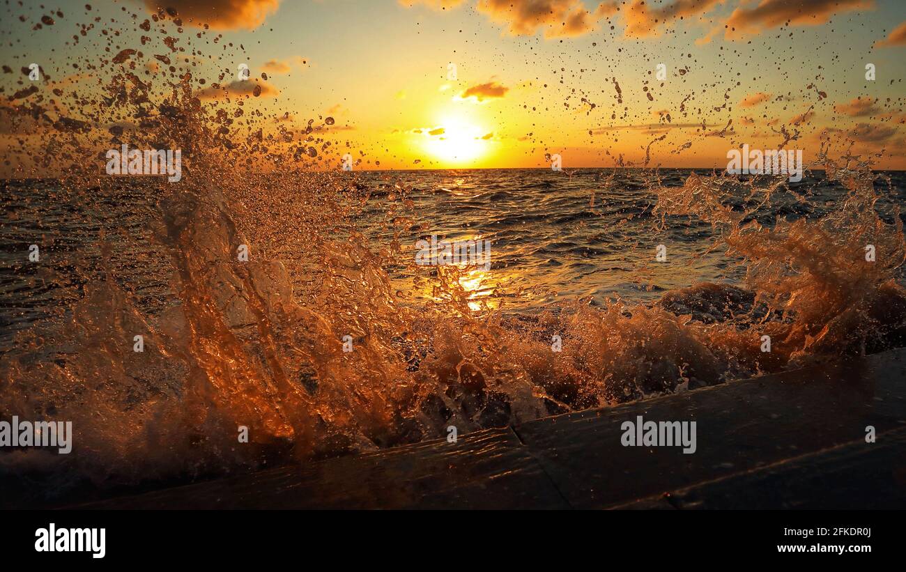 Heacham, UK. 29th Apr, 2021. The setting sun illuminates waves crashing ...