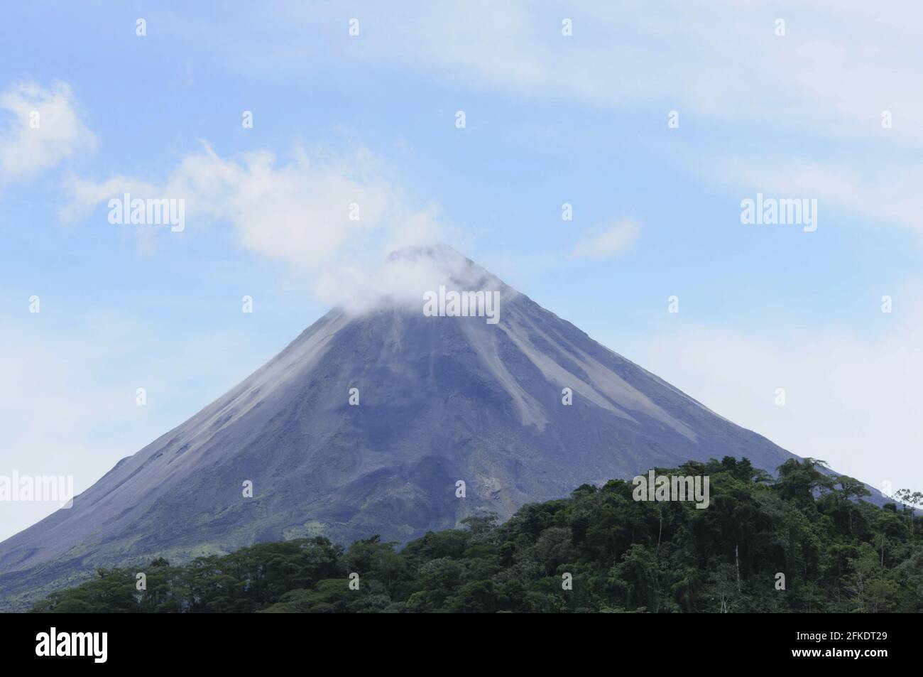 Closeup shot of the Arenal volcano peak with light clouds on top Stock ...