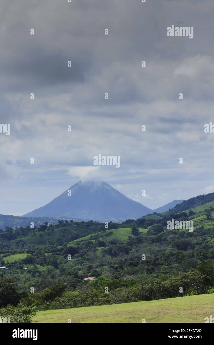 Closeup shot of the Arenal volcano peak and mountains with forests in ...