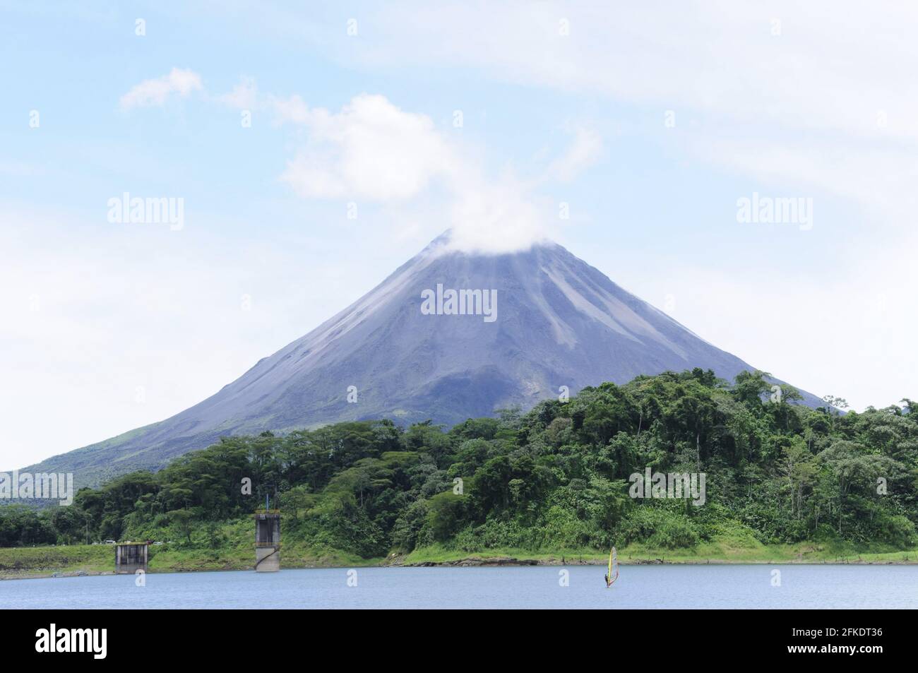 Closeup shot of the Arenal volcano peak and a lake with forests on the ...