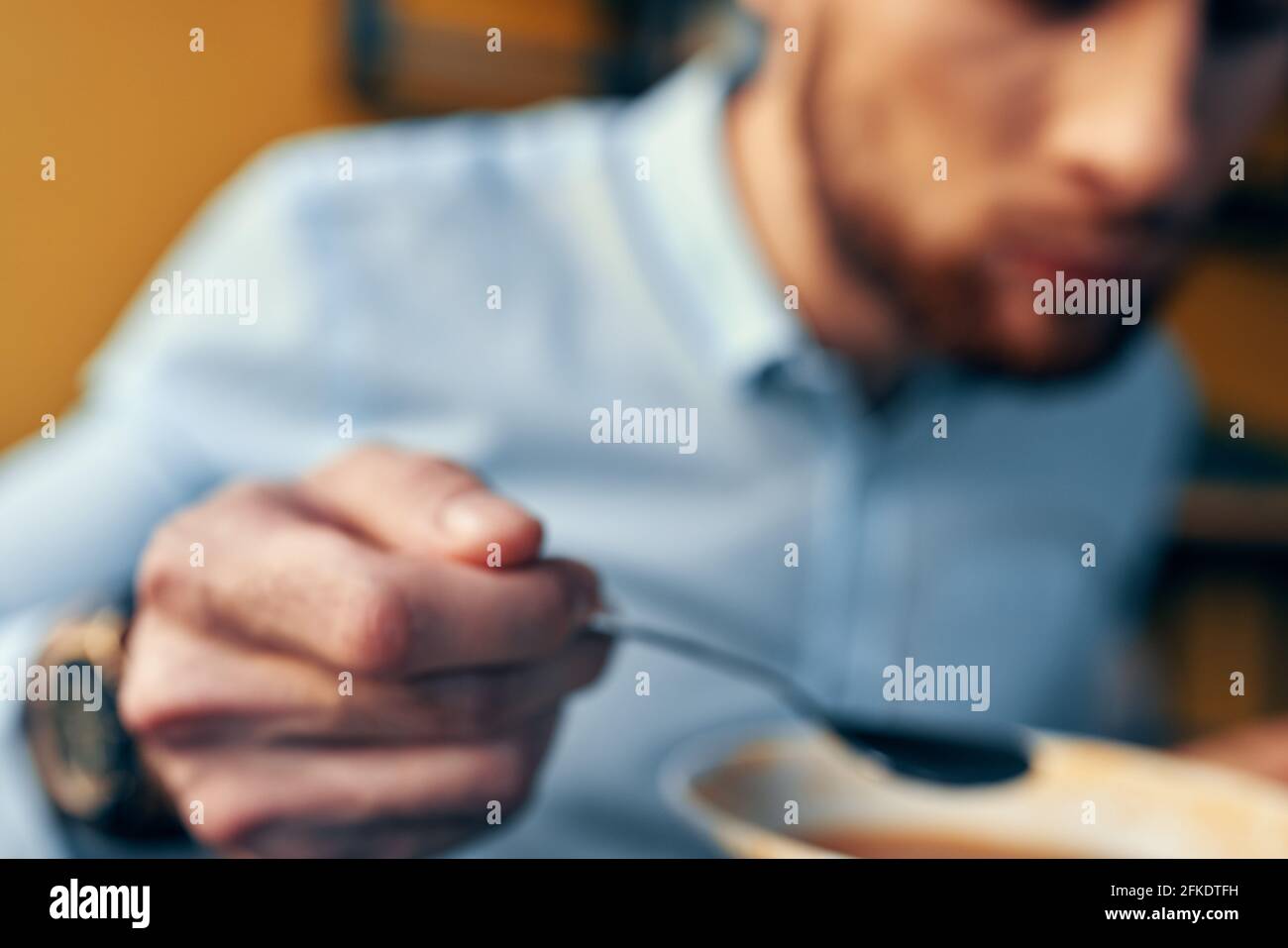 a handsome man with a beard eats borscht in a plate at a table in a ...