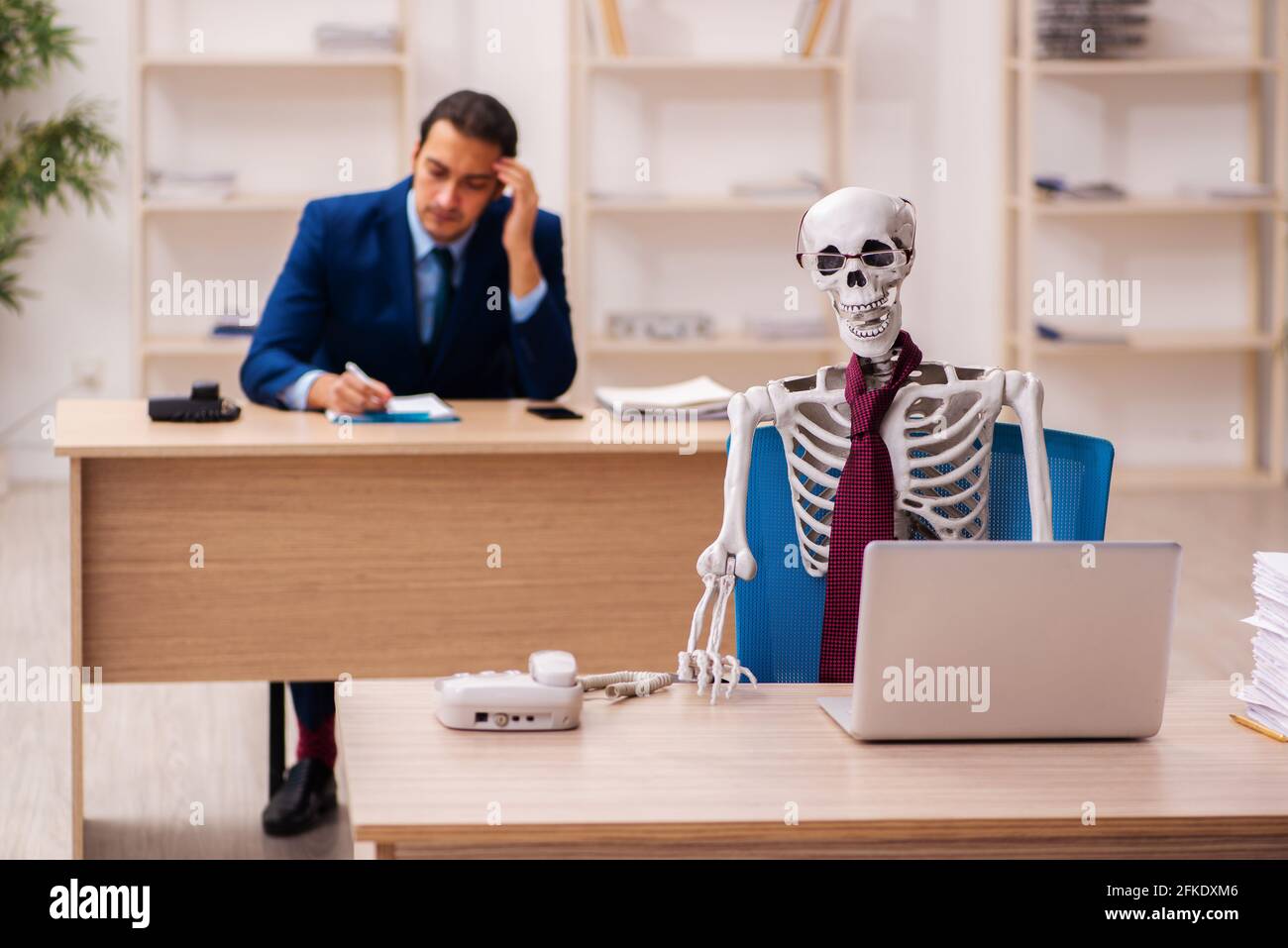 Dead employee working in the office in funny concept Stock Photo - Alamy