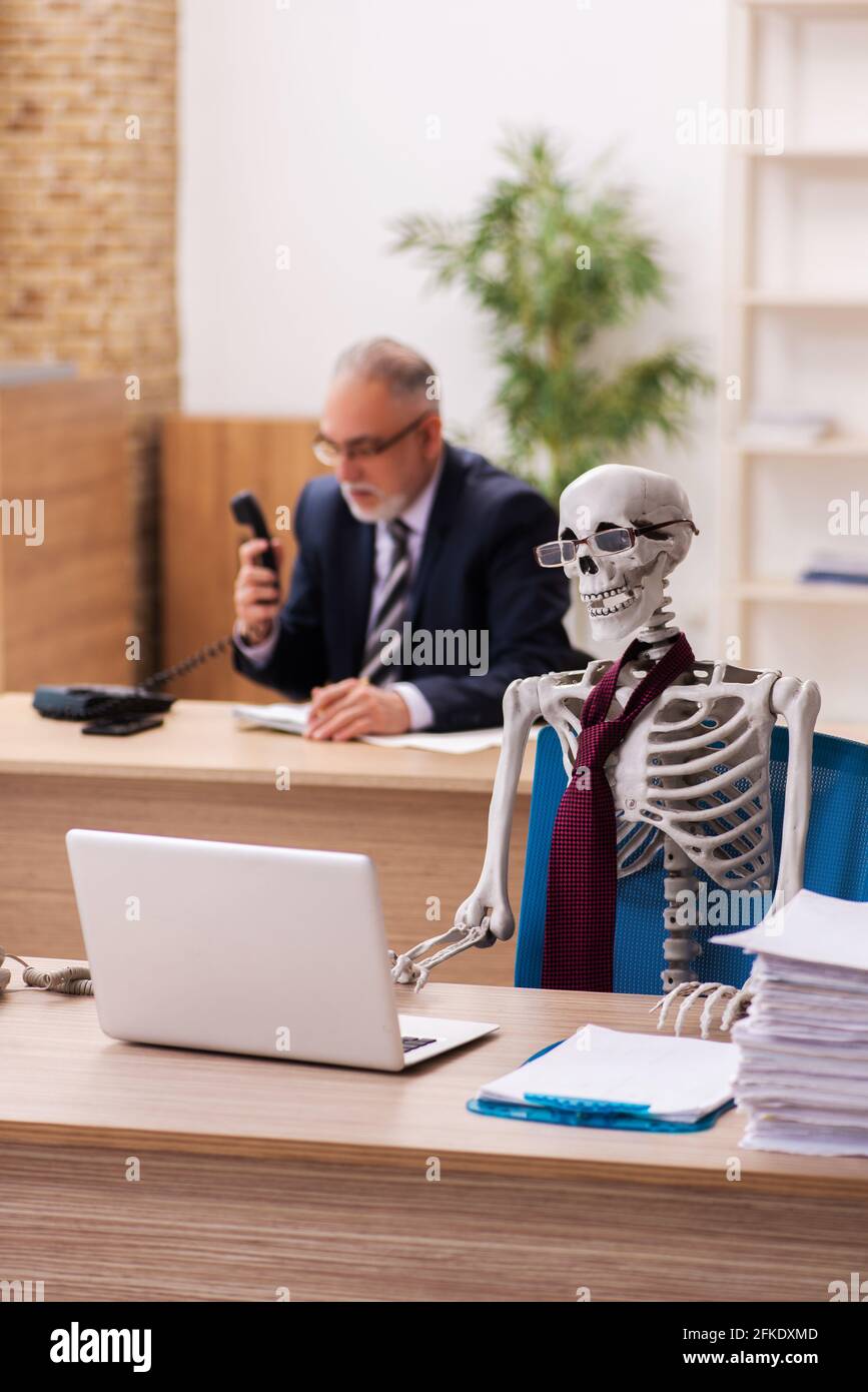 Dead employee working in the office in funny concept Stock Photo - Alamy