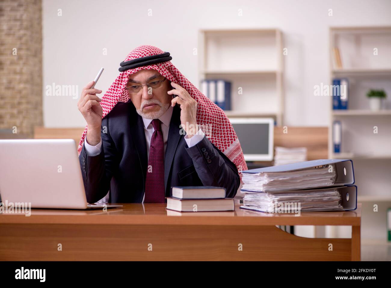 Old male arab employee sitting at workplace Stock Photo - Alamy