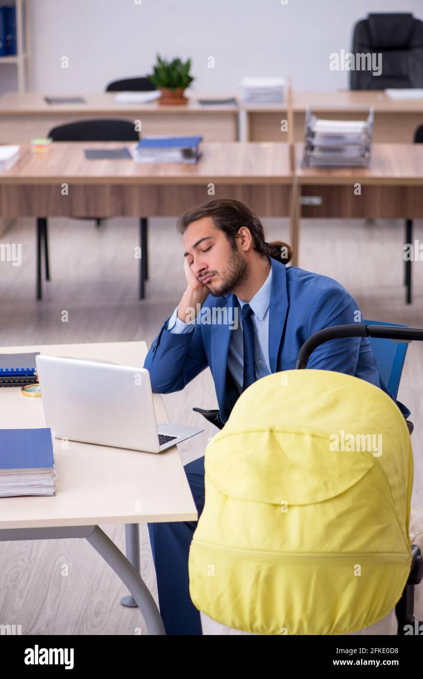 Young male employee looking after new born in the office Stock Photo ...