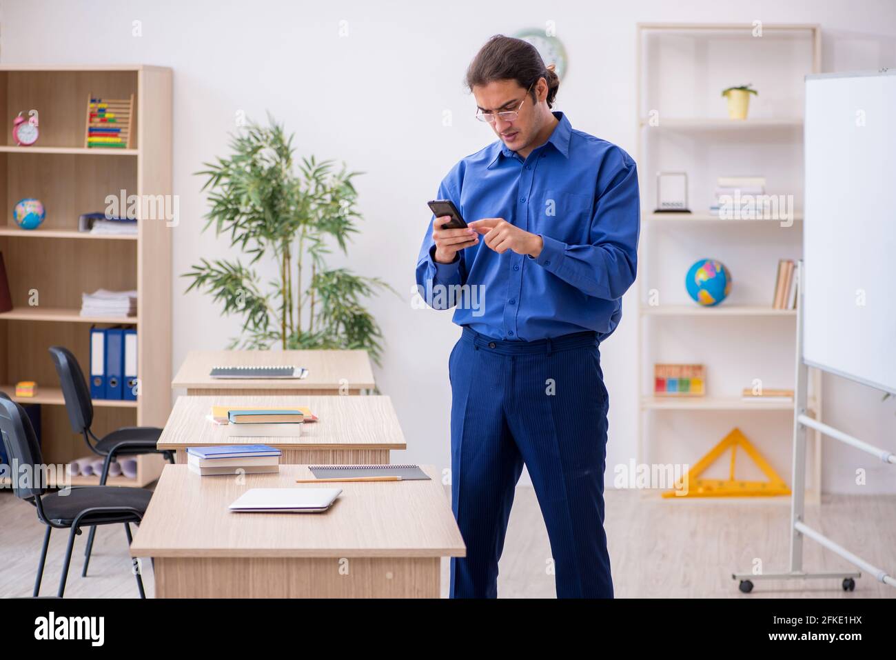 Young teacher holding smartphone during lesson Stock Photo - Alamy