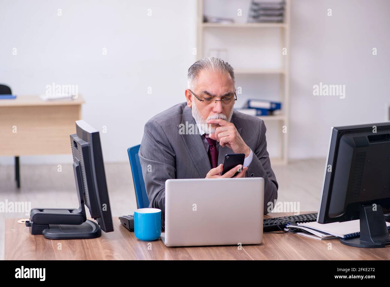 Old boss sitting at desktop in the office Stock Photo - Alamy