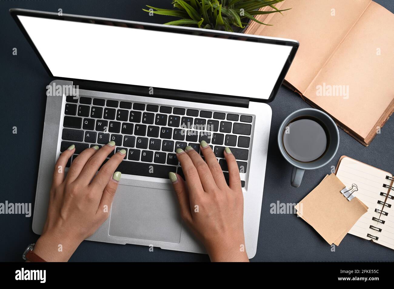 Overhead shot of female hands typing on laptop computer over black ...