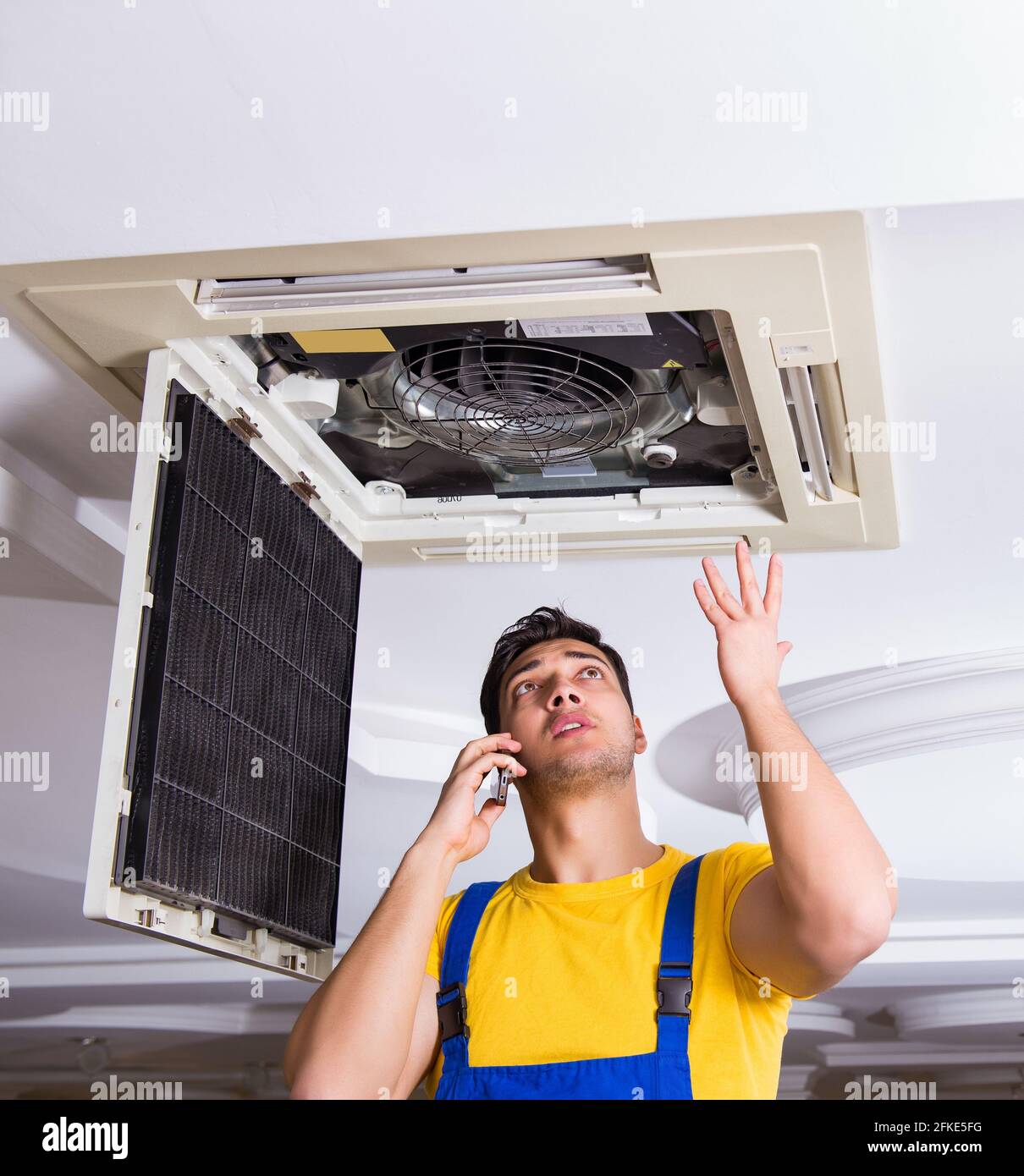 The repairman repairing ceiling air conditioning unit Stock Photo - Alamy