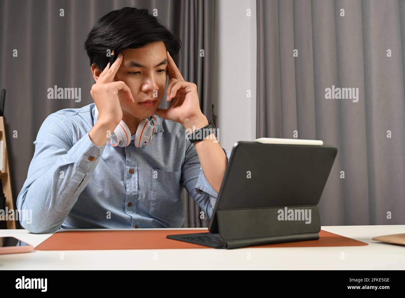 Exhausted businessman looking at tablet computer and feeling stressed ...