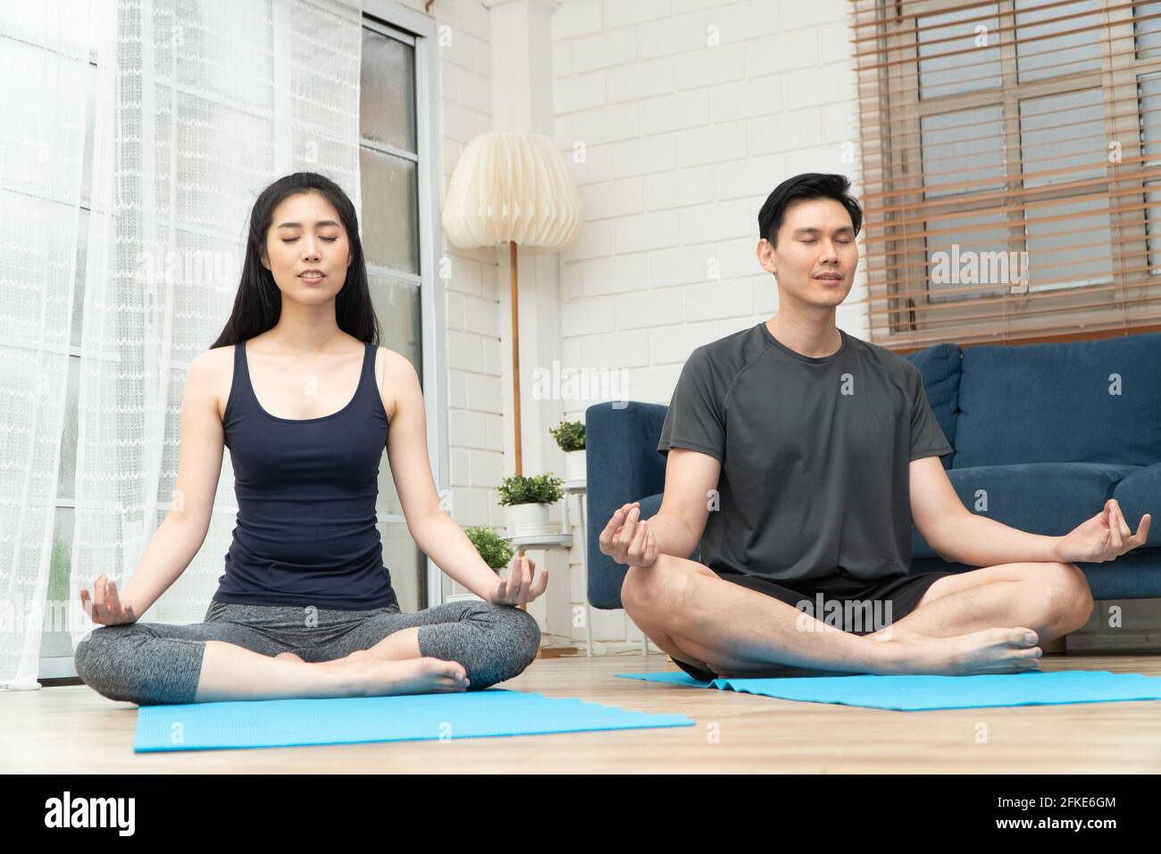 Healthy young Asian couple attractive couple practicing yoga exercises ...