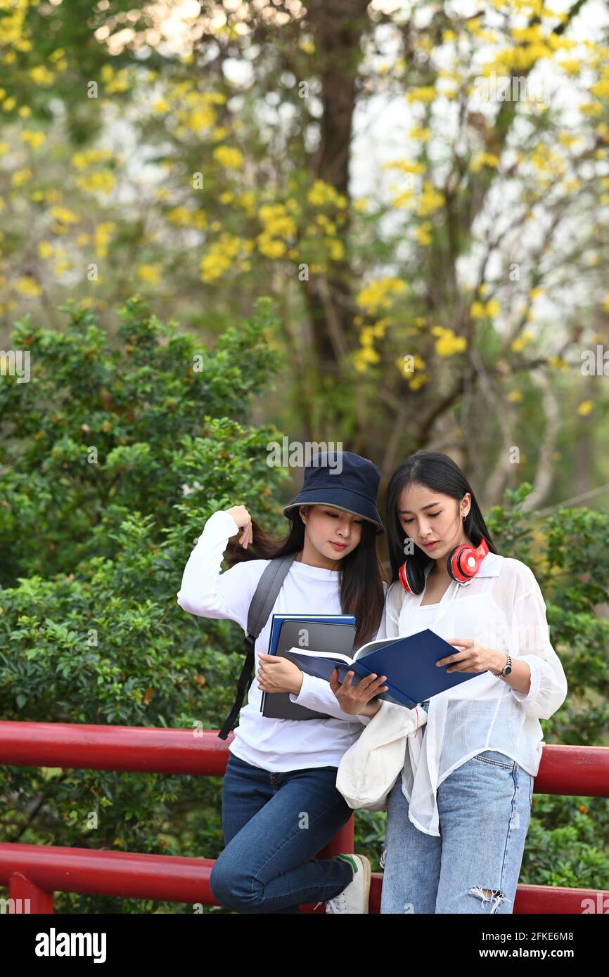 Two asian university student talking about exam results and standing ...