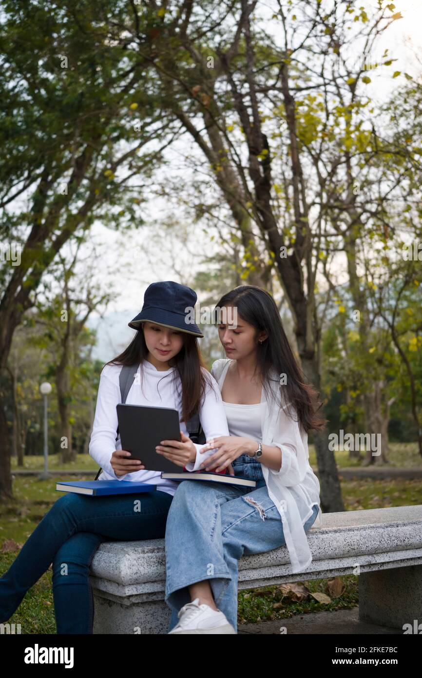 Two university students sitting on bench in park and talking after ...