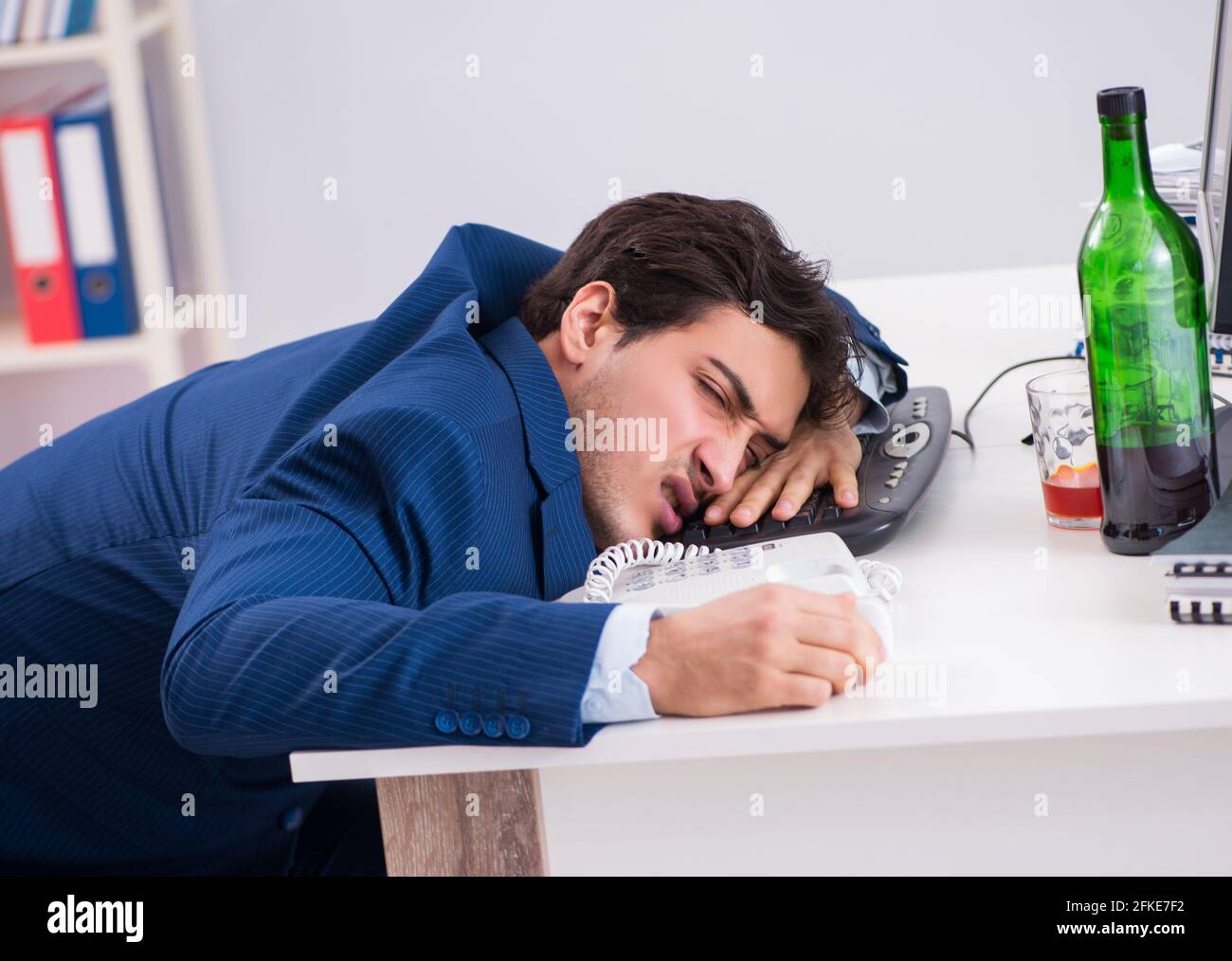 The young businessman employee drinking in the office at desk Stock ...