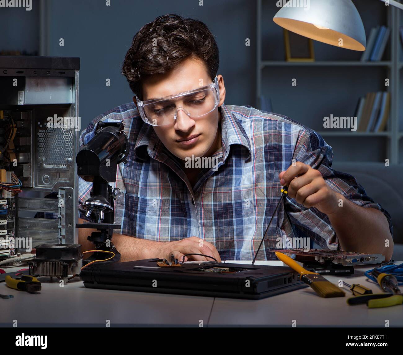 Young repair technician soldering electrical parts on motherboard Stock ...