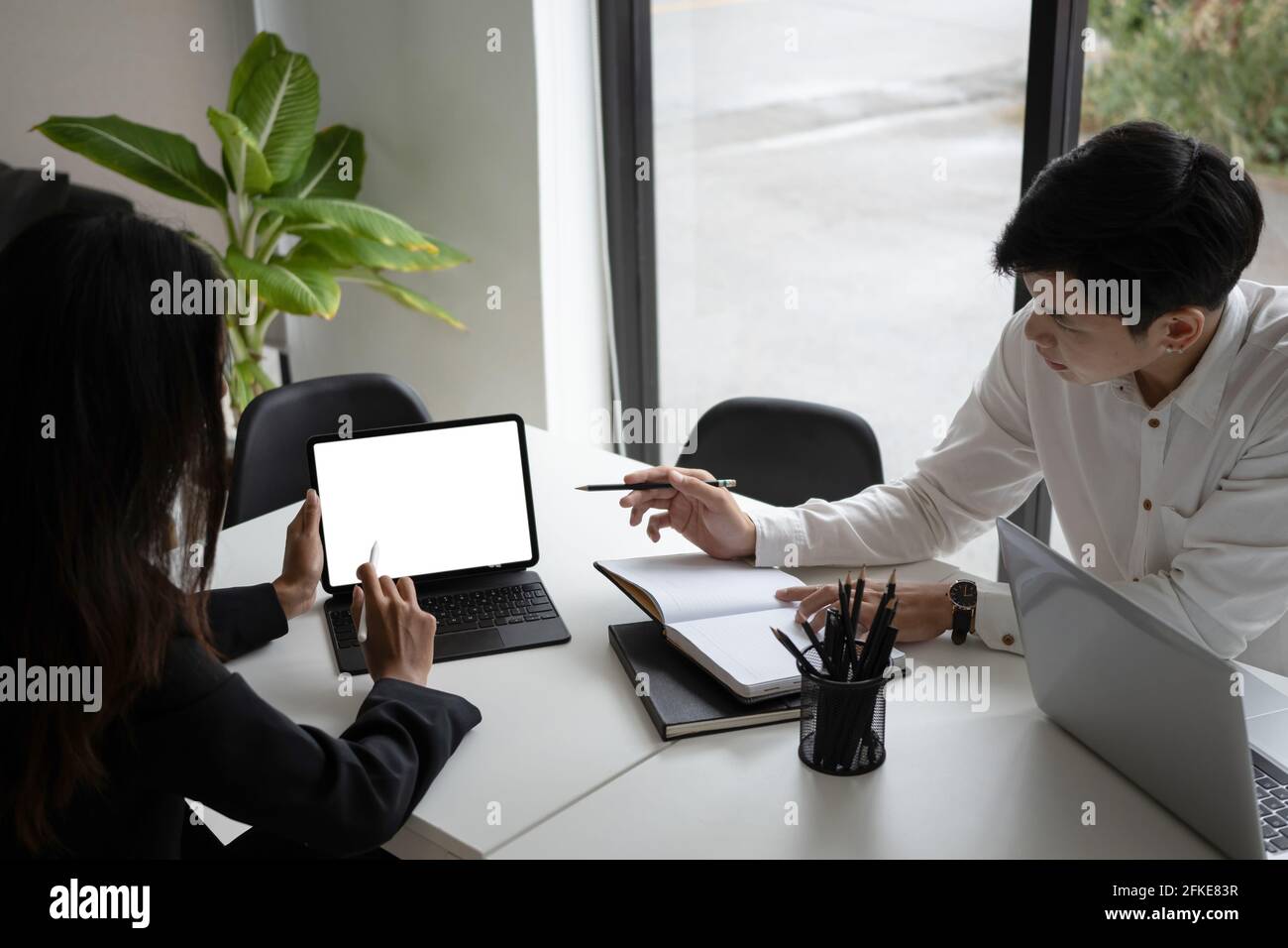 Two young business people discussing business data over computer tablet ...