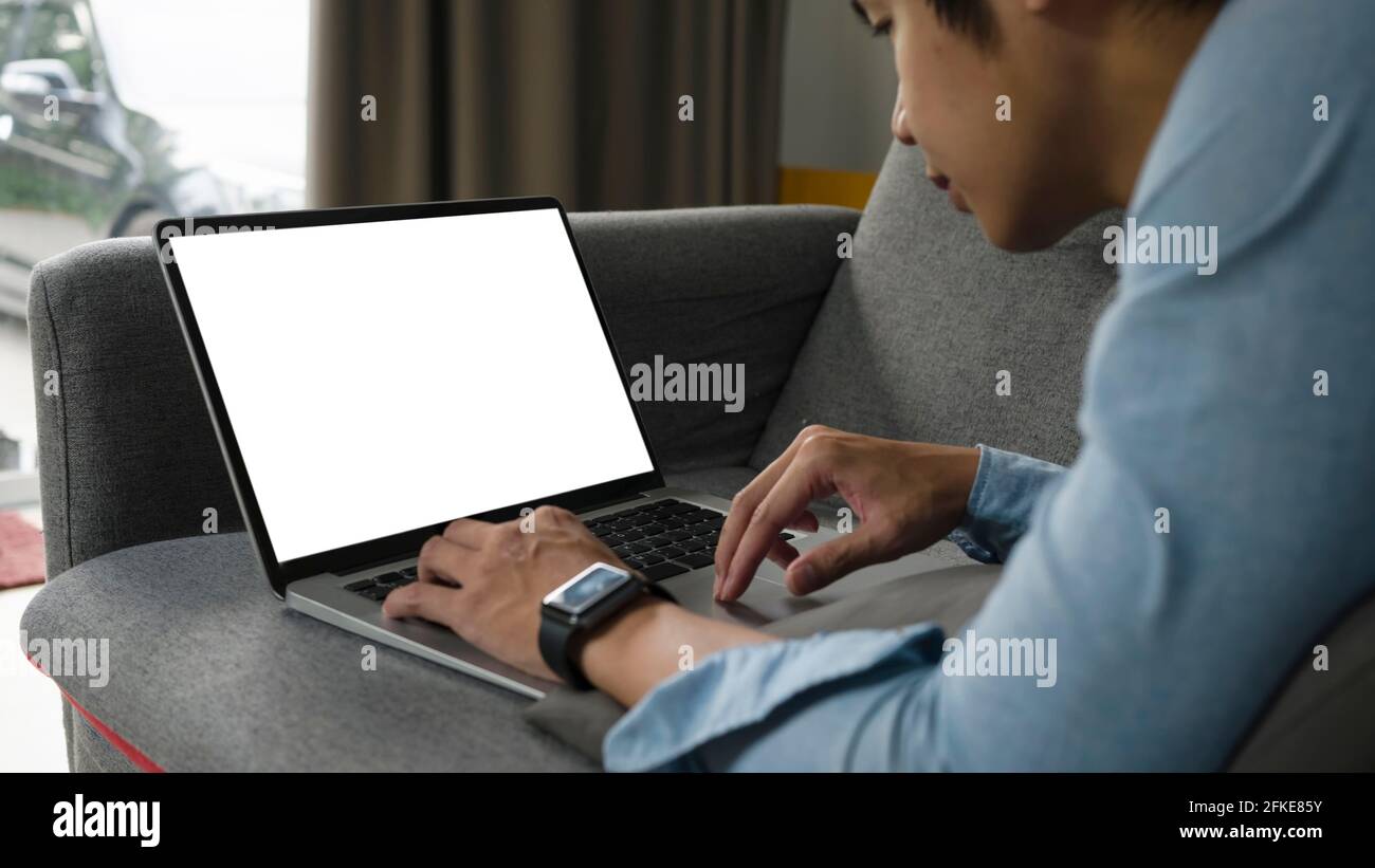 Close up view of your asian man ling on sofa and using computer laptop ...