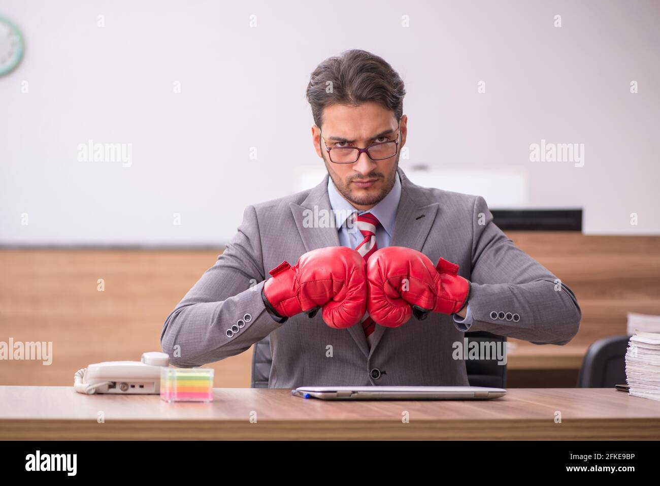 Young businessman employee wearing boxing gloves at workplace Stock ...