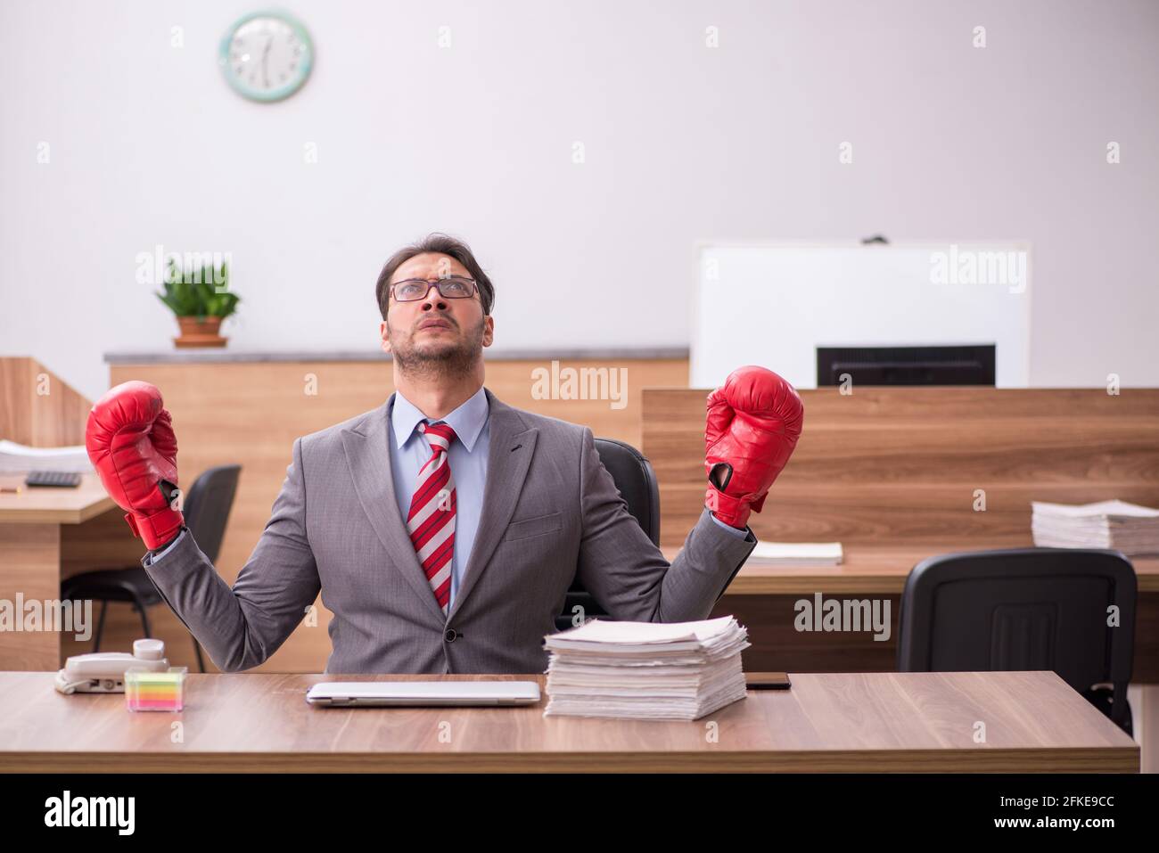 Young businessman employee wearing boxing gloves at workplace Stock ...