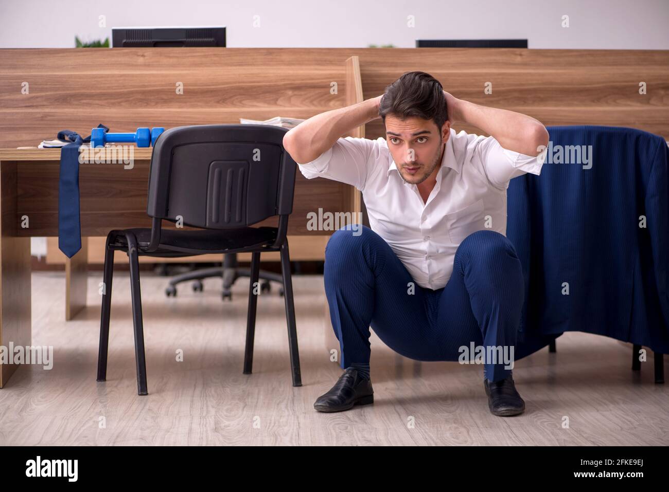 Young male employee doing sport exercises in the office Stock Photo - Alamy