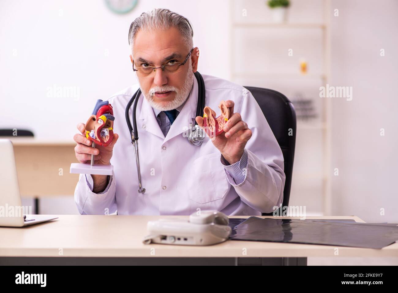 Aged male doctor cardiologist working at workplace Stock Photo - Alamy