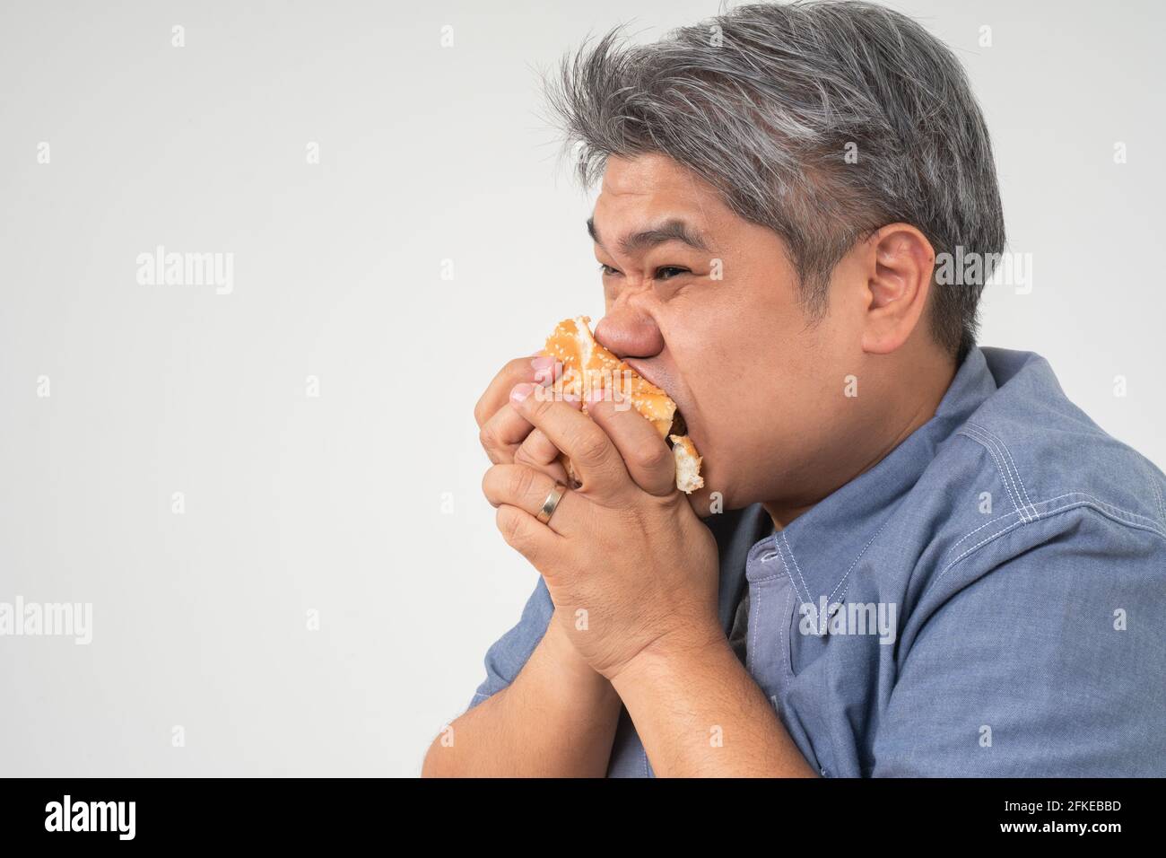 Asian Middle aged man holds and eating a hamburger deliciously Concept ...