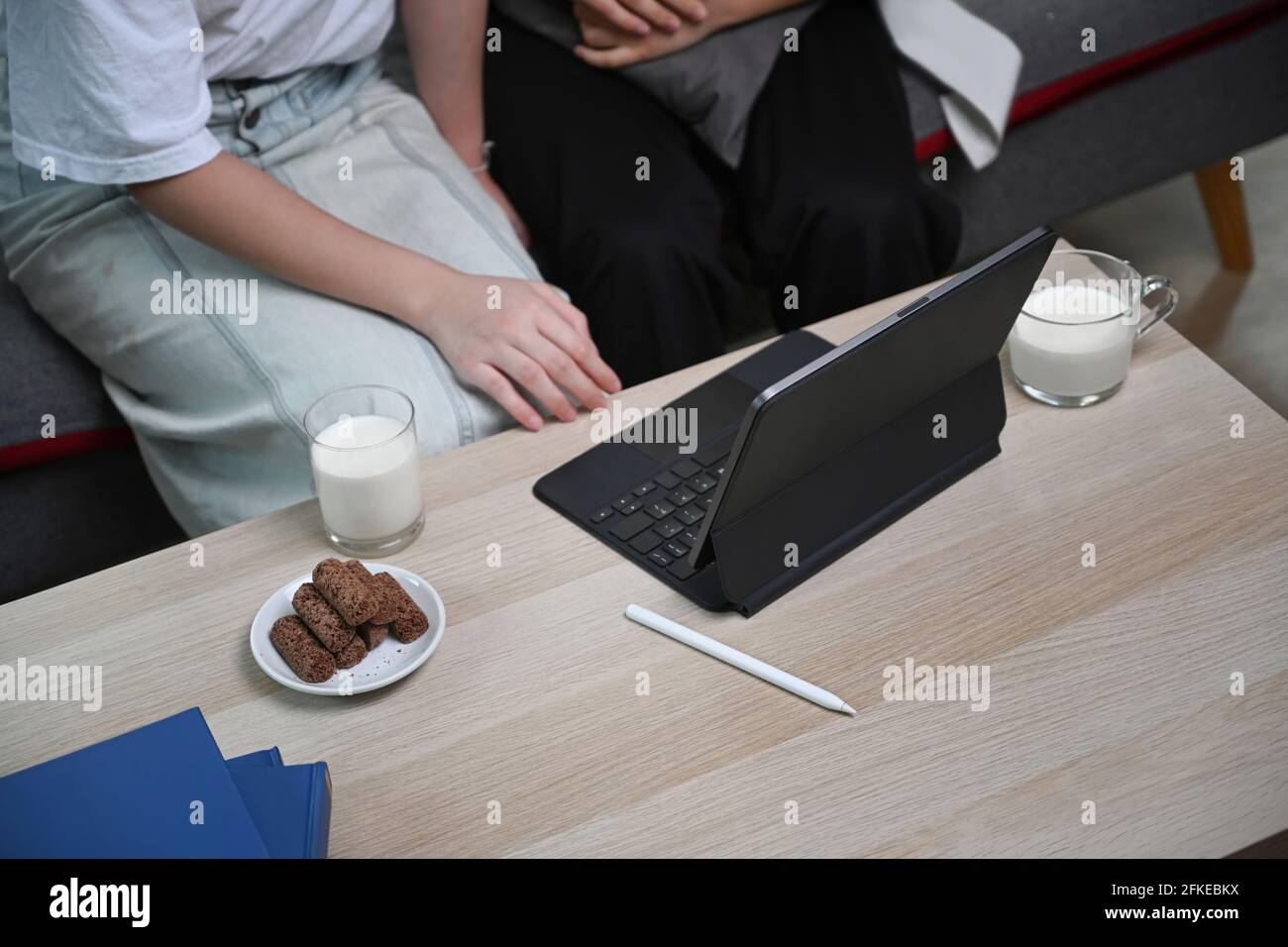 Two young woman using computer tablet and sitting together on sofa at ...