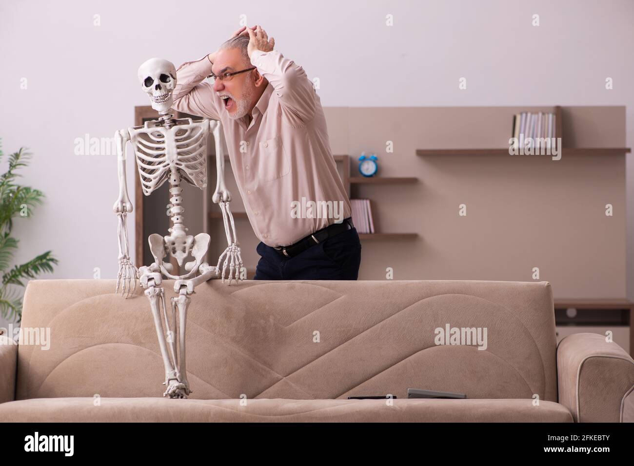 Old man sitting on the sofa with the female skeleton in undying love ...