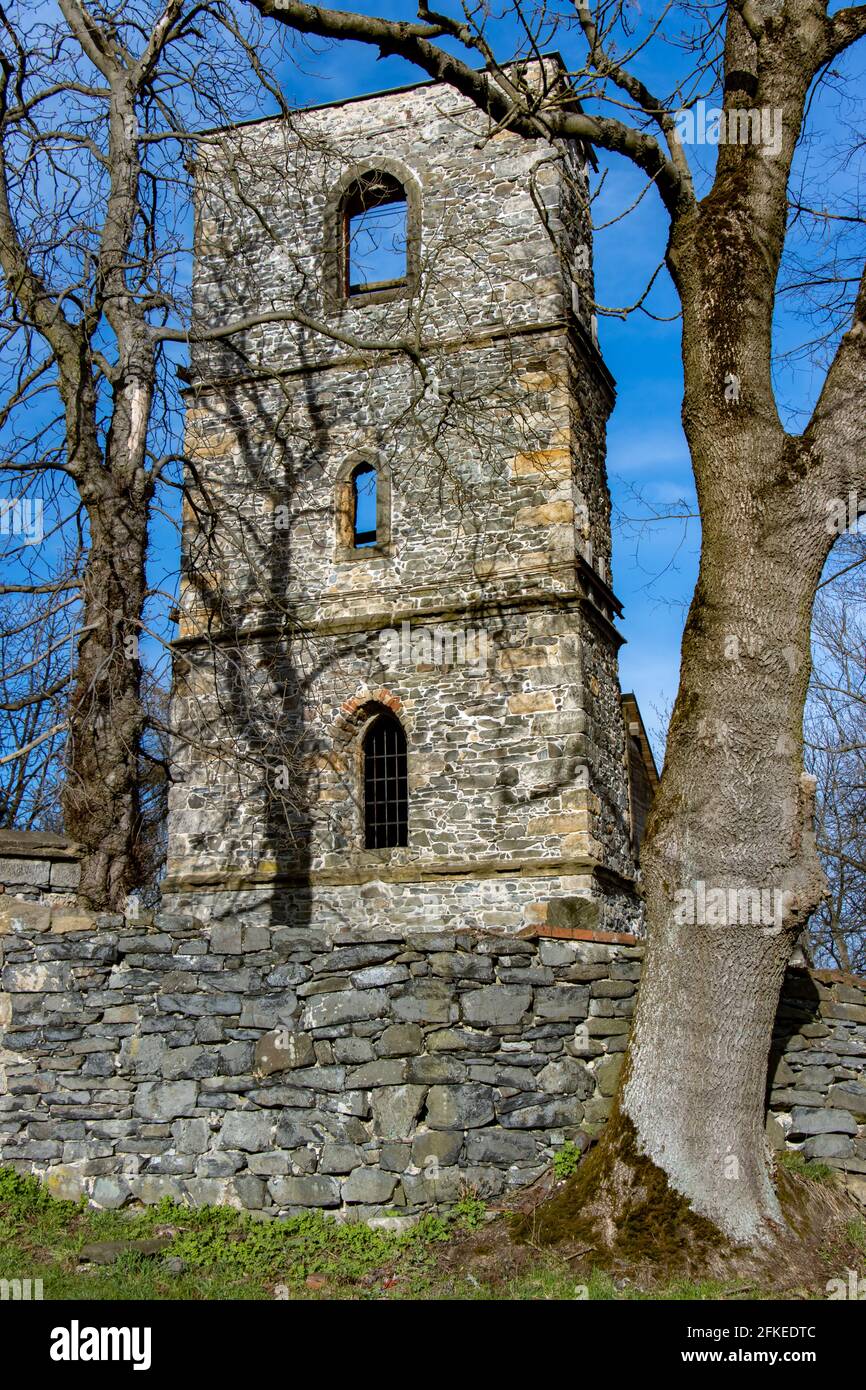A half-demolished stone church behind the enclosure wall with blue sky ...