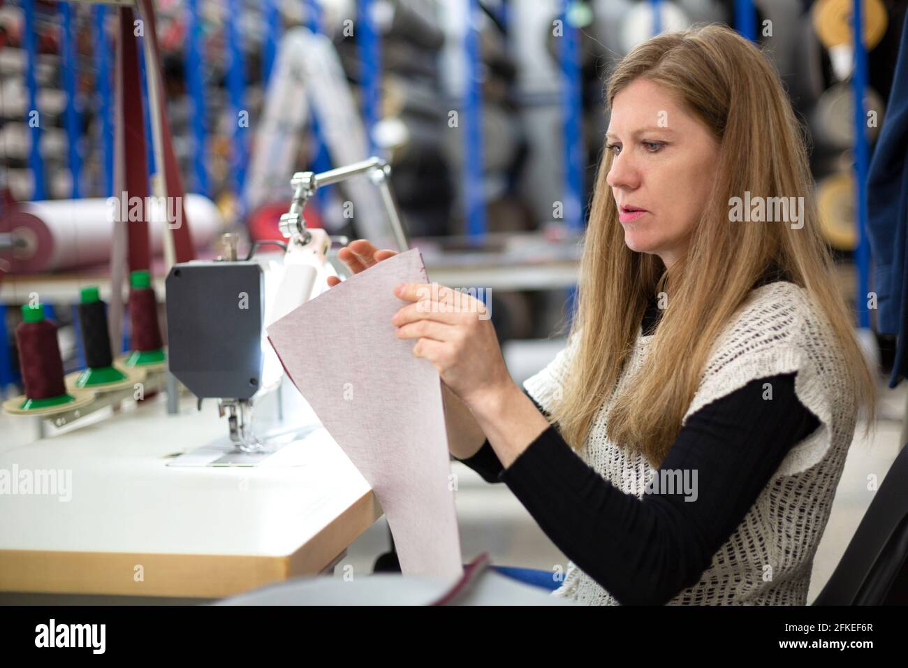 Caucasian woman working in a textile factory. She is sitting next to ...