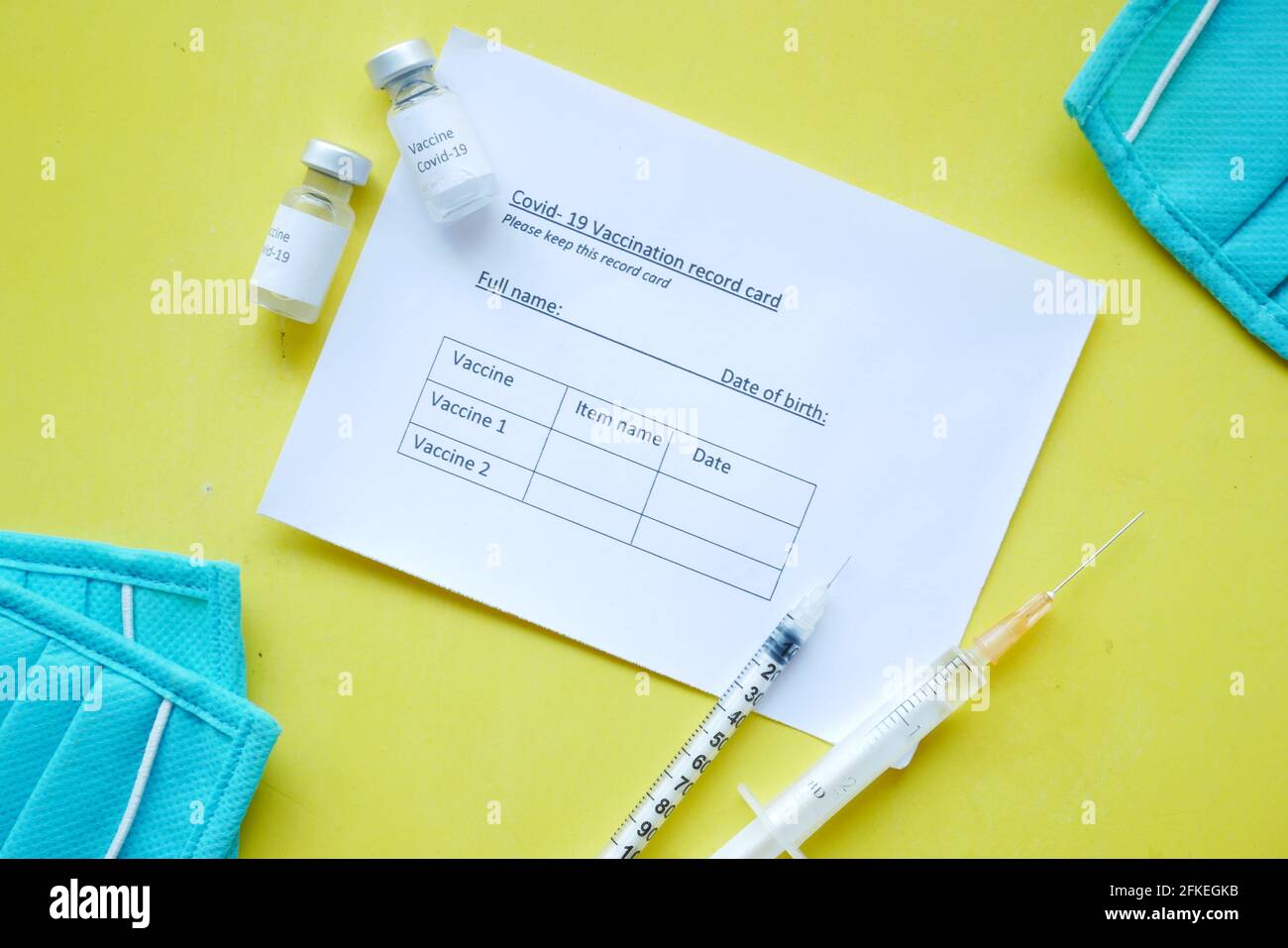 vaccination record card , vaccine , syringe and mask on yellow Stock ...