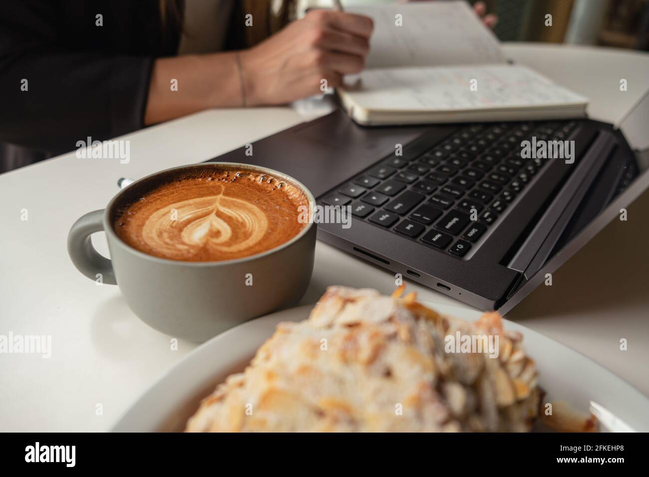 Beautiful lady is drinking coffee while working on a laptop in a coffee ...