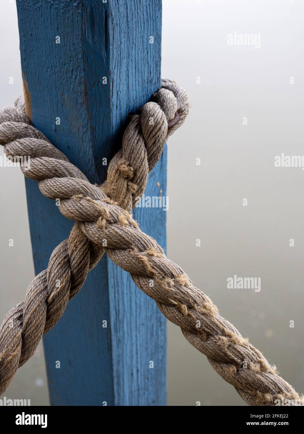 Vertical shot of a rope tied around a blue wooden column Stock Photo ...