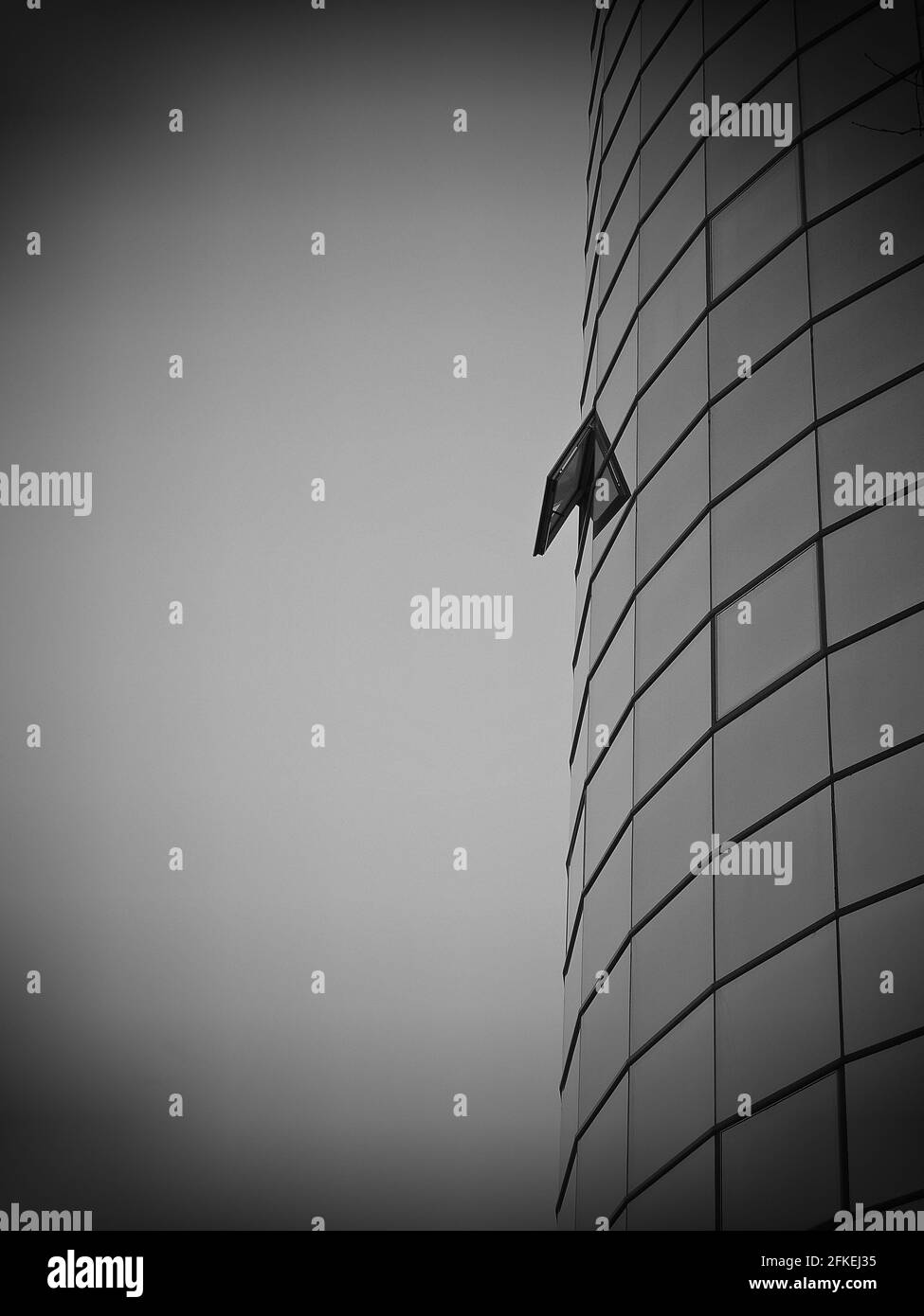 Vertical greyscale shot of one open glass window on a modern building ...
