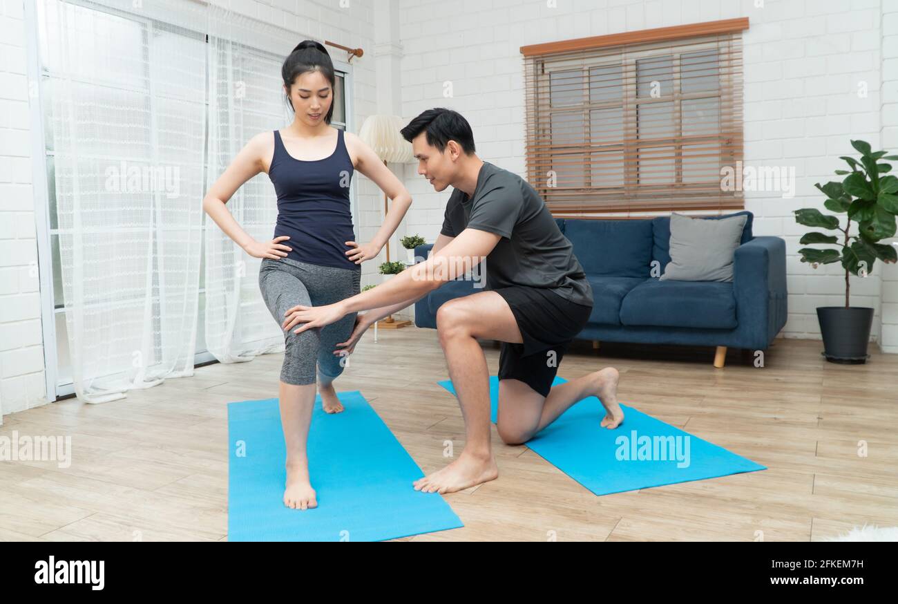 Healthy young Asian couple exercises in home and husband teaching him a ...