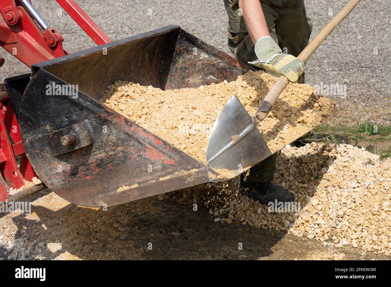 part of a construction worker digs a gravel with a metal shovel on the ...