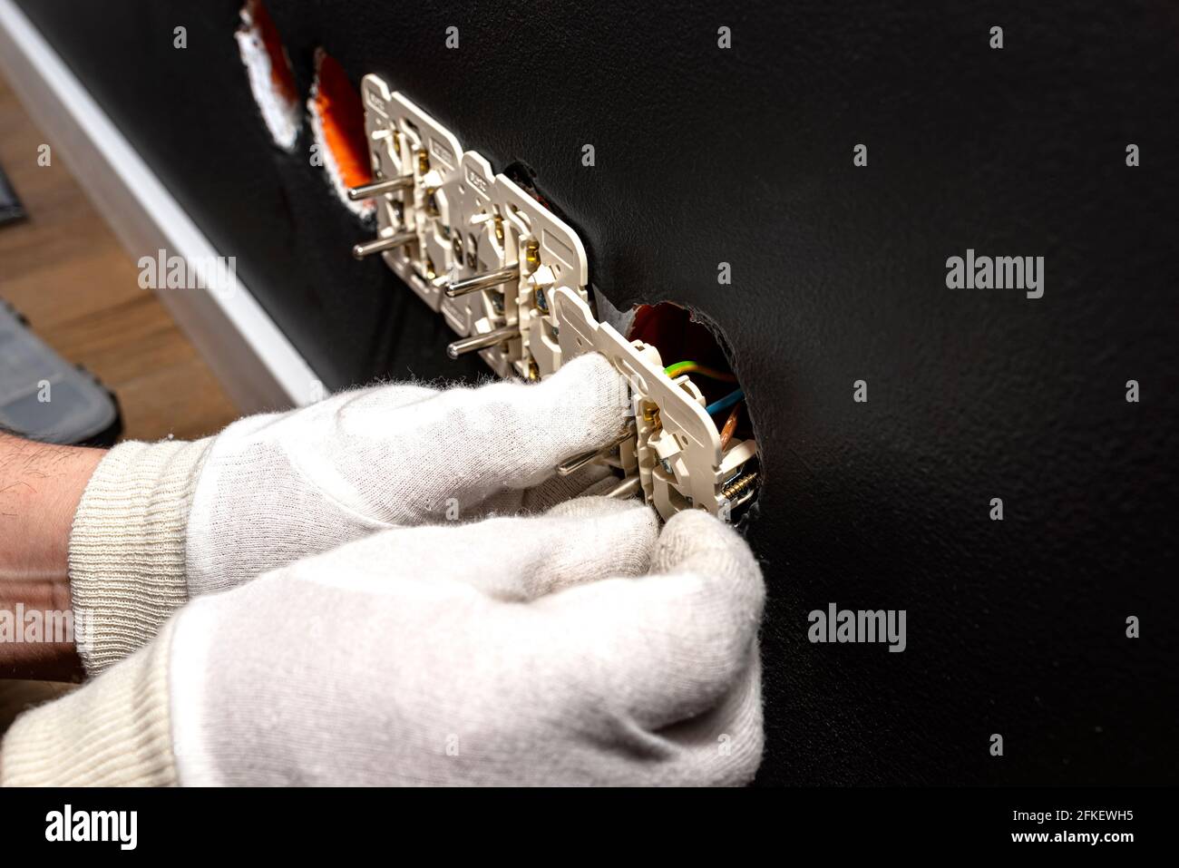 An electrician inserts a double grounded electrical socket into an ...