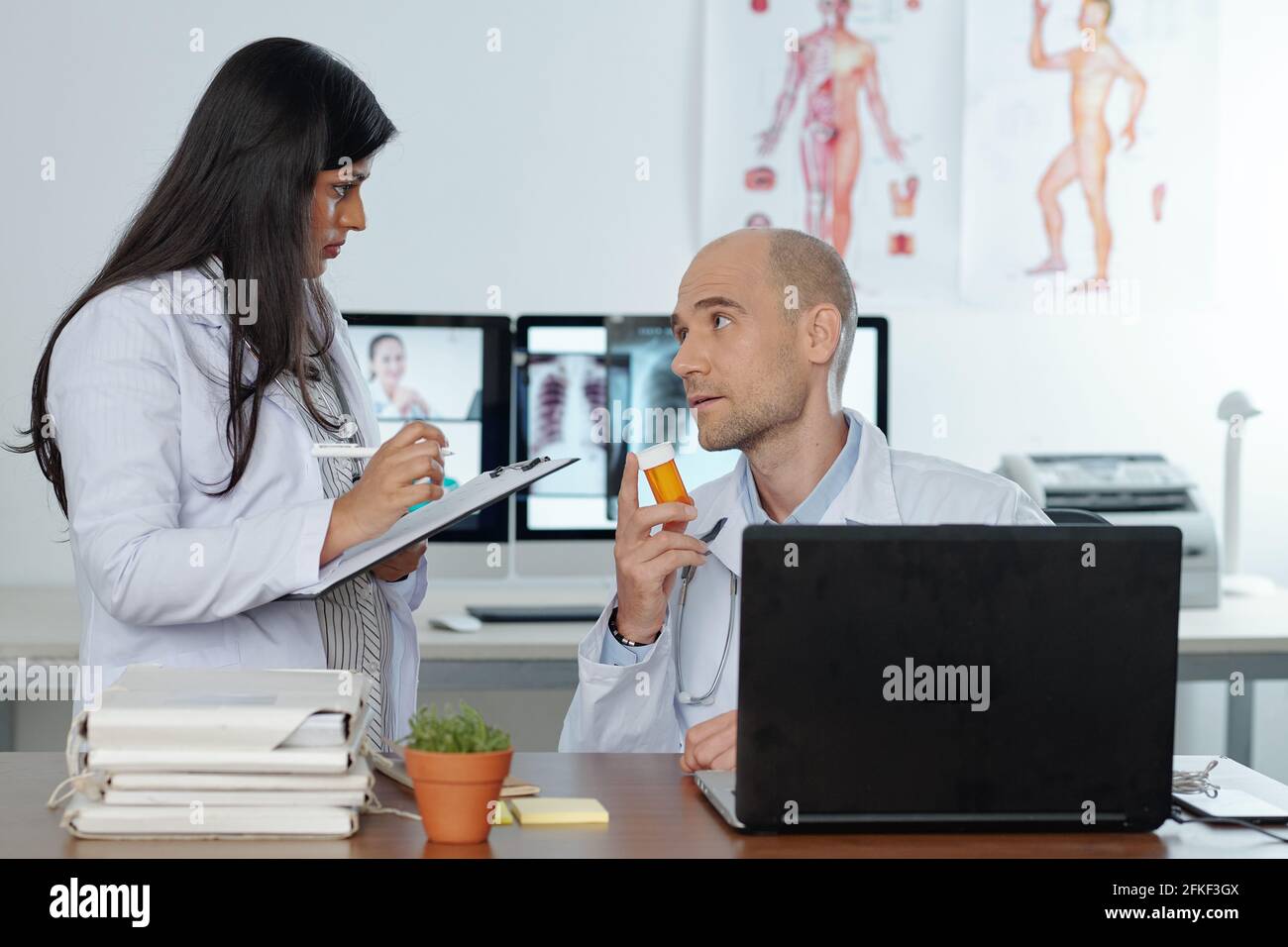 Physician recommending bottle of new pills to his collegue who is ...