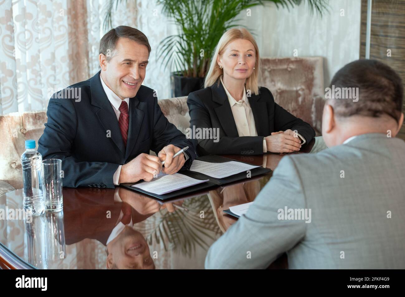 A group of people sitting around table in boardroom and negotiating ...