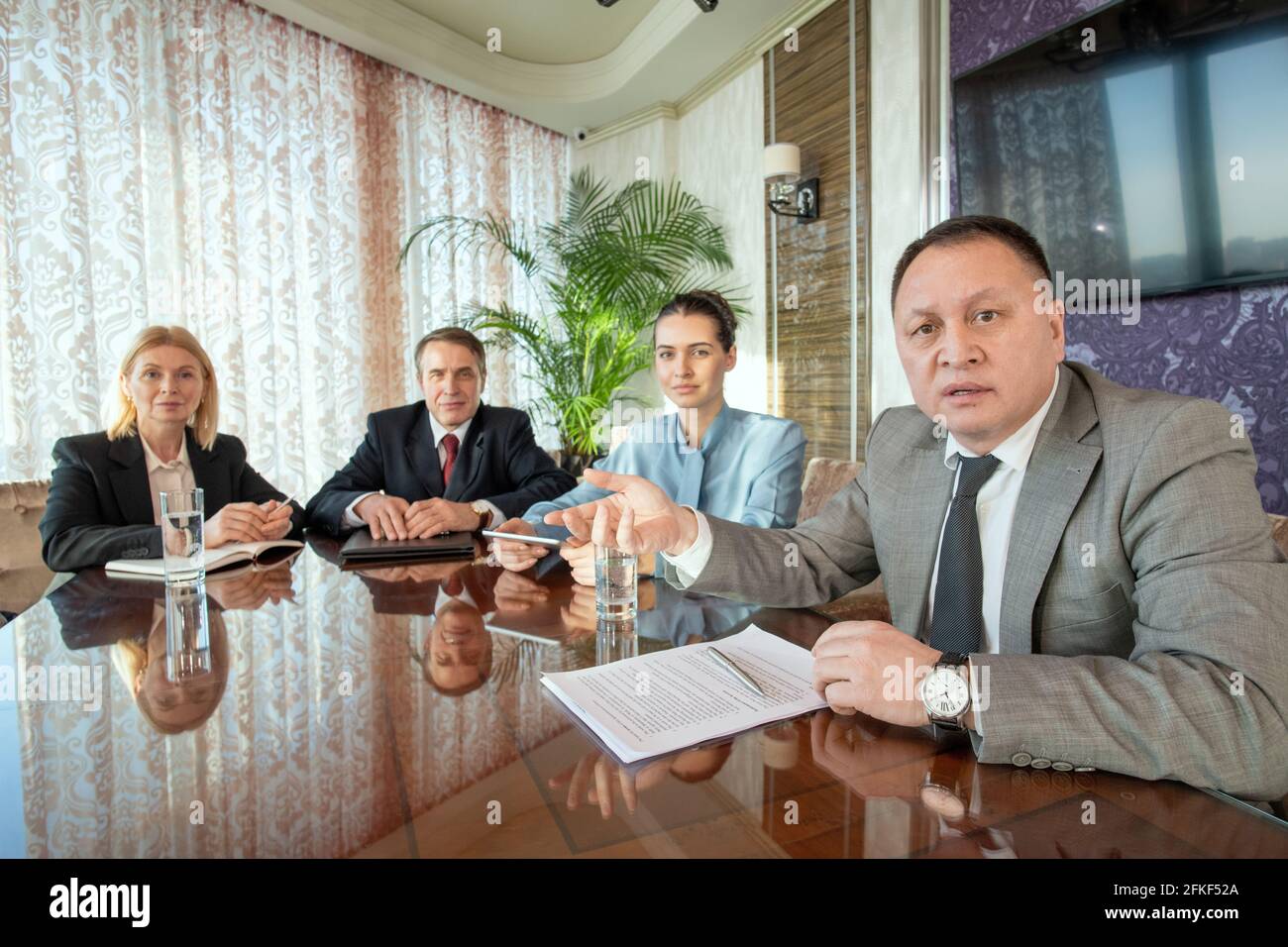 A group of people sitting at a table in boardroom and looking at you ...