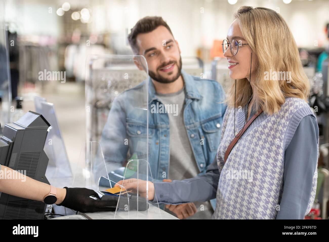 A man and a woman paying for clothes during shopping in department ...