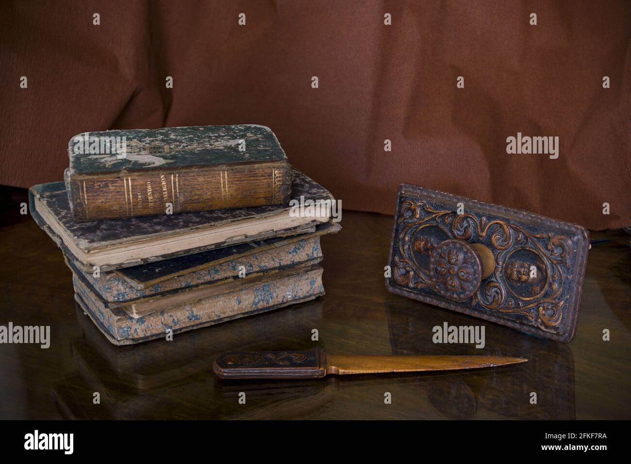 View at a stack of ancient stained books by a metallic artifact and an ...